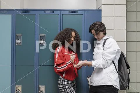 High school girl writing on hand of boy at lockers Stock Photo #201888205