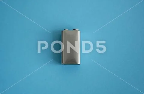 High voltage battery on a blue background. Silver Volt battery. 9V ...