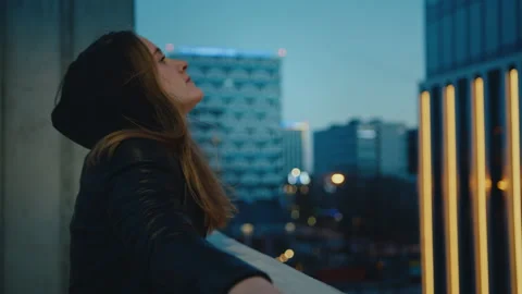 Hooded woman at edge of rooftop looks to... | Stock Video | Pond5