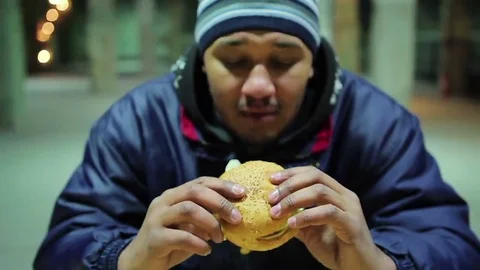Hungry homeless man eating tasty burger.... | Stock Video | Pond5