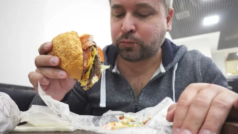 Hungry man eating big hamburger in fast ... | Stock Video | Pond5