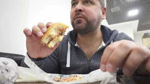 Hungry man eating big hamburger in fast ... | Stock Video | Pond5