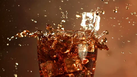 Ice cubes fall into a glass with cola. | Stock Video | Pond5