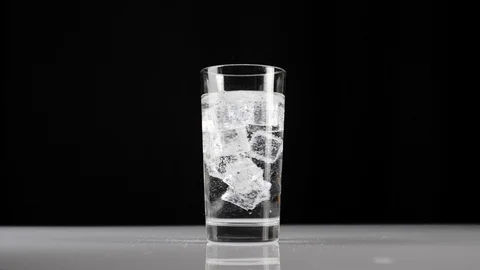 Ice cubes spin and float in a glass with... | Stock Video | Pond5