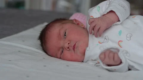 Infant baby girl lying on side looking a... | Stock Video | Pond5