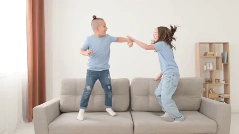 Joyful brother and sister jumping on sof... | Stock Video | Pond5