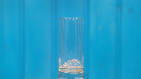 Juice falling in a glass with ice cubes | Stock Video | Pond5