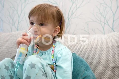 Kid girl makes inhalation with a nebulizer. sick child holding ...