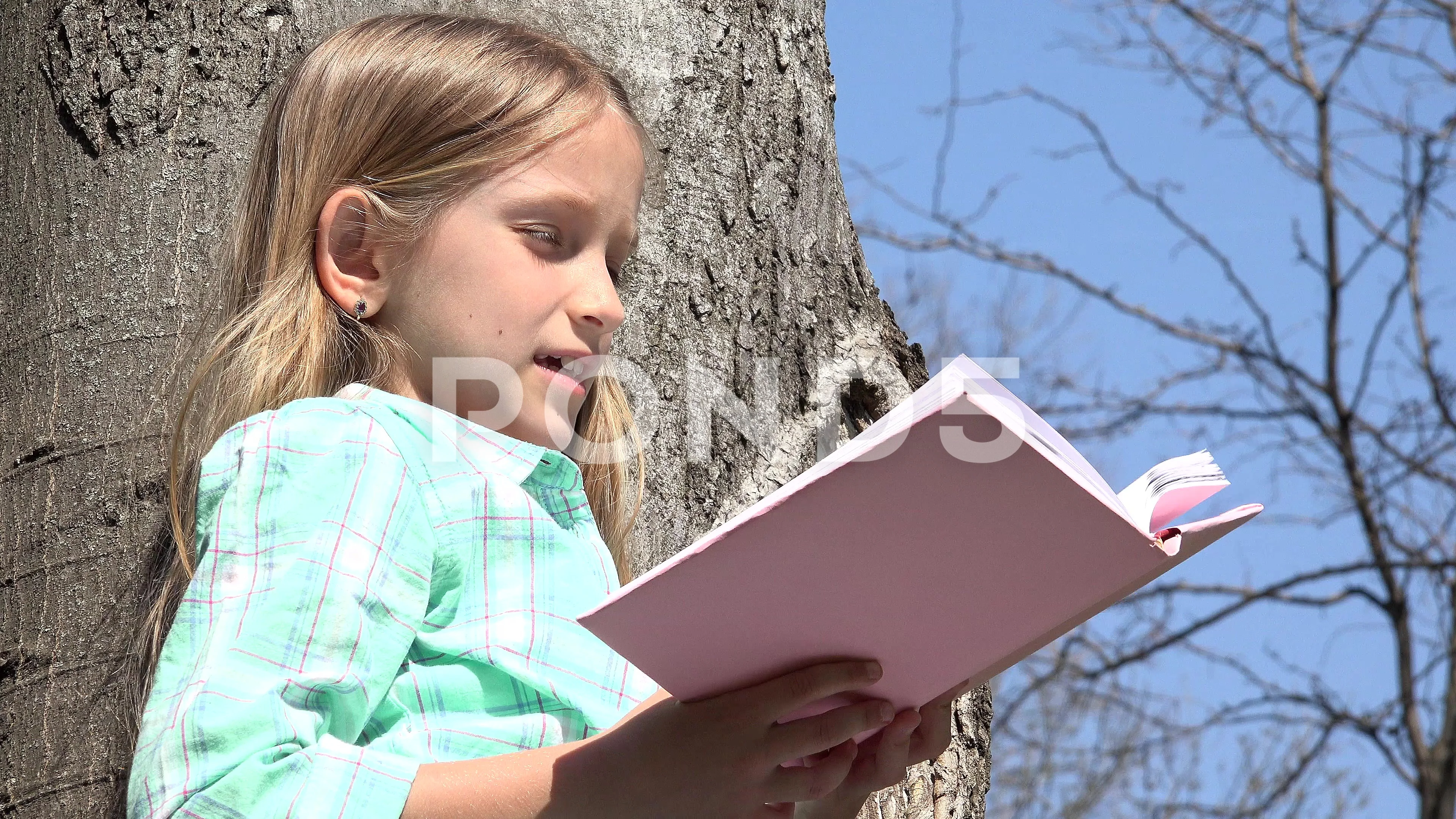 Little Girl Reading A Book Under A Tree