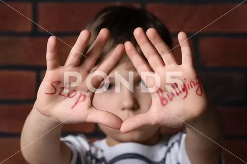 Photograph: Kid showing hands with phrase Stop Bullying near brick wall ...