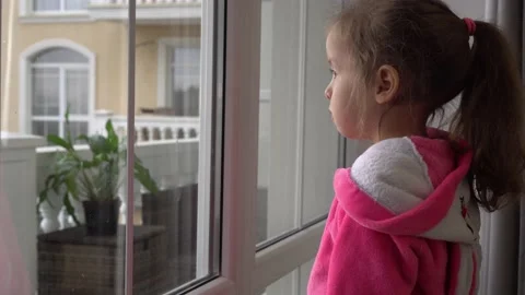 Kid sits alone on sill and looks out win... | Stock Video | Pond5