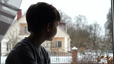 kid sitting on the window sill and looki... | Stock Video | Pond5