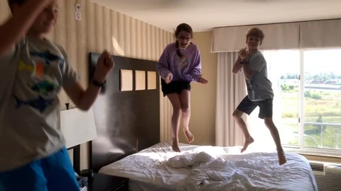 Kids dancing on beds in hotel room laugh... | Stock Video | Pond5