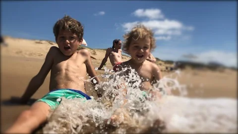Kids playing at the beach with ocean wav... | Stock Video | Pond5