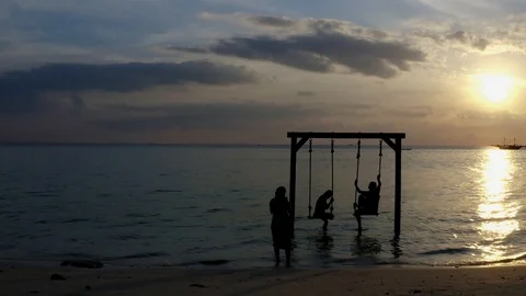 Kids playing on ocean swing at beach, su... | Stock Video | Pond5