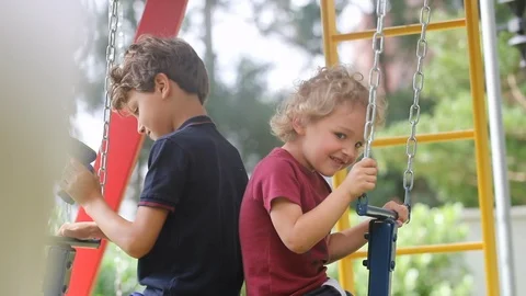 Kids playing at playground swing outside | Stock Video | Pond5