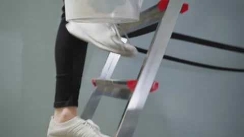 Lady goes up step ladder holding paint b... | Stock Video | Pond5