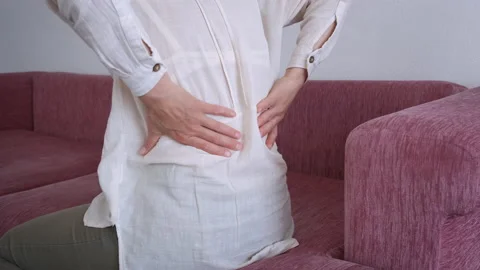 Lady suffering from back pain on sofa. | Stock Video | Pond5