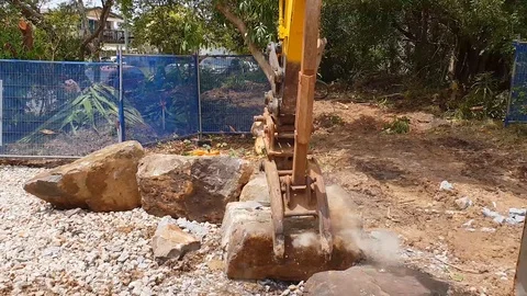 A large excavator lifting a heavy boulde... | Stock Video | Pond5