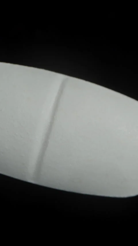 A large white pill rotates on a black ba... | Stock Video | Pond5
