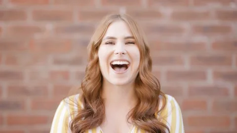 Laughing young woman in front of brick w... | Stock Video | Pond5