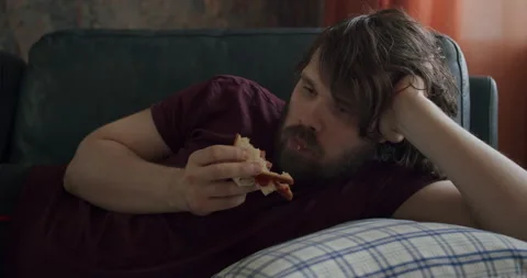 Lazy beard man eating sandwich on the co... | Stock Video | Pond5