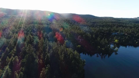 Lens Flare on Flyover of Forest Surround... | Stock Video | Pond5