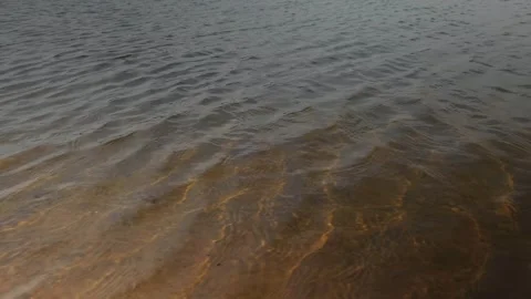 Light waves splash on the sandy shore of... | Stock Video | Pond5