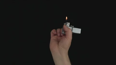 Lighter is lit in a male hand on a black... | Stock Video | Pond5