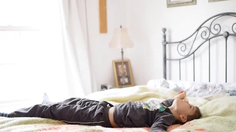 Little boy laying on bed kicking feet | Stock Video | Pond5