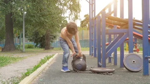 Little boy lifting heavy weight on the o... | Stock Video | Pond5