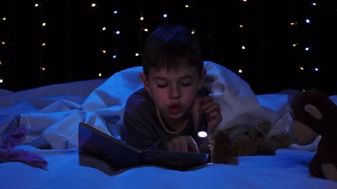 Little boy at night reading a book on th... | Stock Video | Pond5
