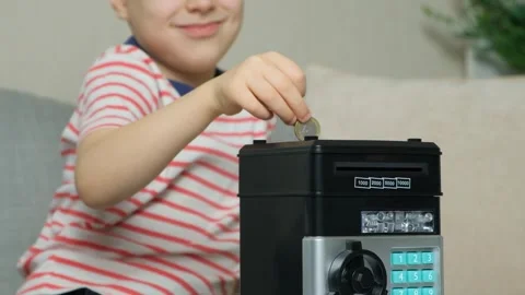 A little boy puts a coin into a safe pig... | Stock Video | Pond5