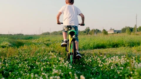 Little boy rides bike in park on green g... | Stock Video | Pond5