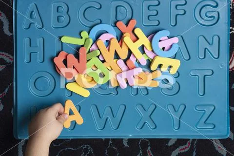 A little child hand sorting the educational colorful spongy letters ...