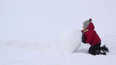 Little child pushing a big snowball, det... | Stock Video | Pond5