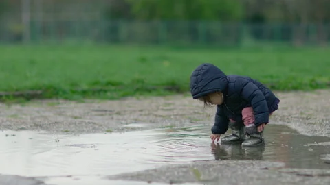 Little child walk through puddle. | Stock Video | Pond5
