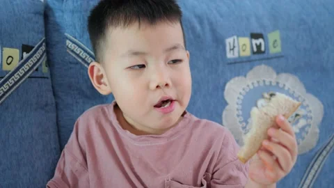 A little Chinese boy eats a toast panel ... | Stock Video | Pond5