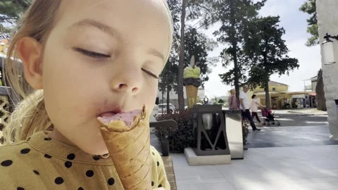 Little girl chewing on a waffle cup with... | Stock Video | Pond5