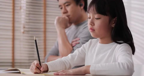 Little girl doing homework and father wo... | Stock Video | Pond5