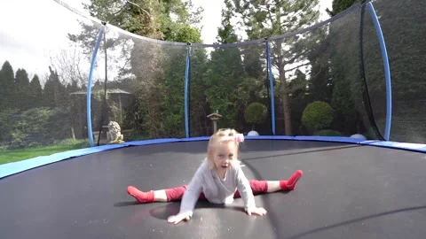 Little girl doing splits on a trampoline... | Stock Video | Pond5