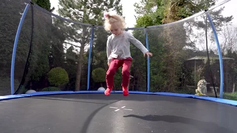 Little girl doing splits on a trampoline... | Stock Video | Pond5