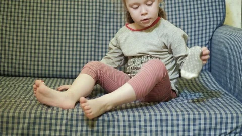 Little girl dressing her socks sitting o... | Stock Video | Pond5