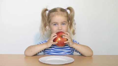 little girl eating an apple while sittin... | Stock Video | Pond5