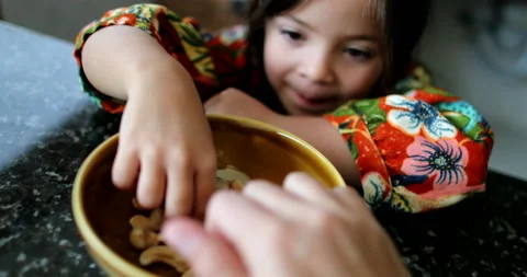 Little girl eating cashew nuts from bowl... | Stock Video | Pond5