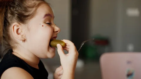 A little girl is eating pickle at the ta... | Stock Video | Pond5