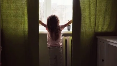 Little girl goes to the window and opens... | Stock Video | Pond5