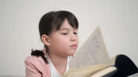 Little girl laying on the bed reading bo... | Stock Video | Pond5