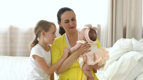 Little girl with mother touching baby in... | Stock Video | Pond5