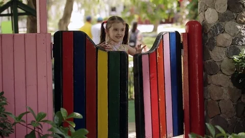 A little girl opens bright colorful gate... | Stock Video | Pond5